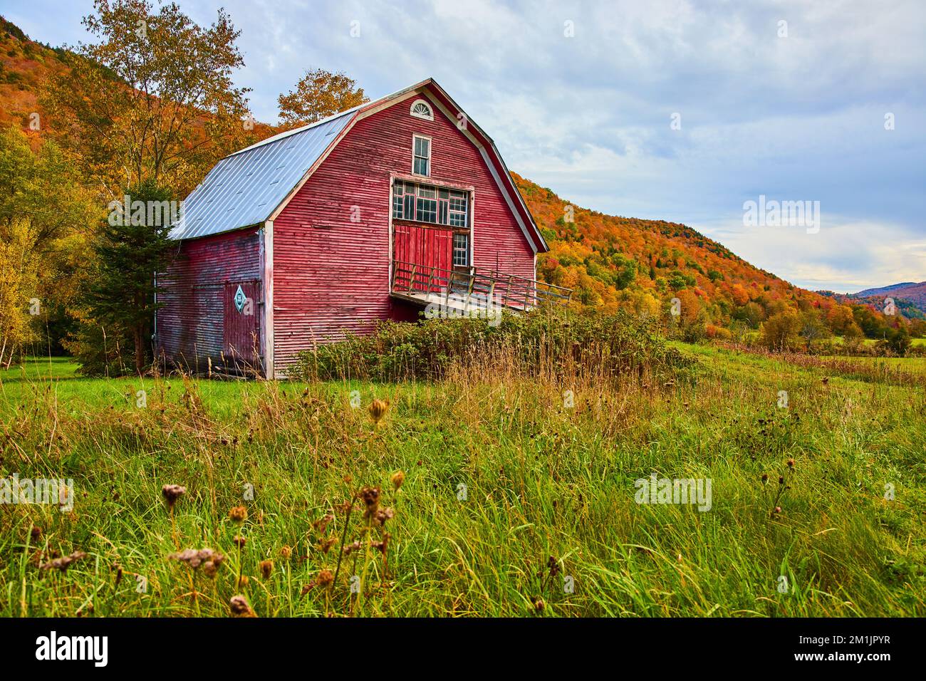 Red barn in country fields surrounded by mountains of peak fall foliage ...