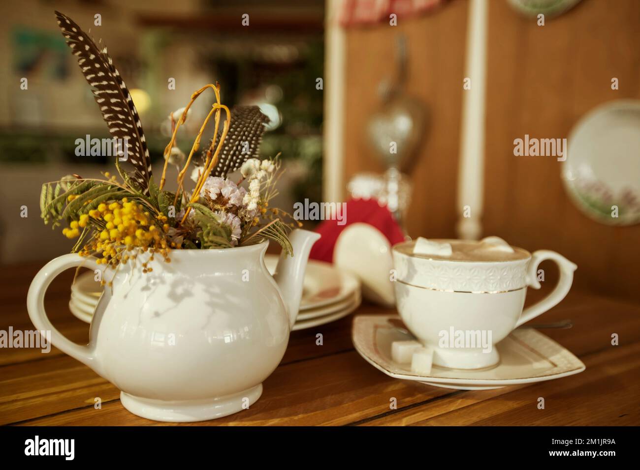On a table in a cafe there is a vase with flowers and exotic feathers ...