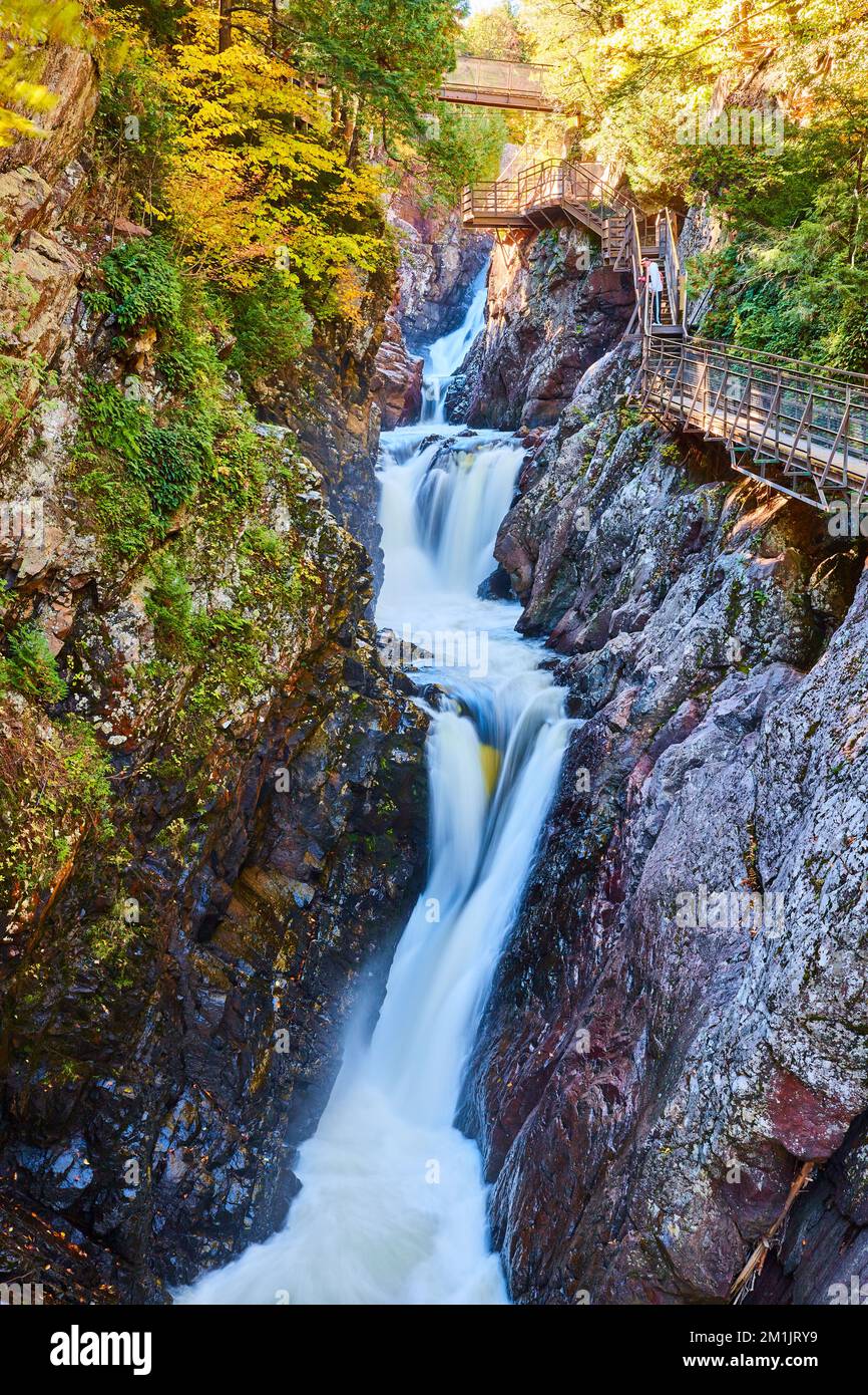Fall forest and cliffs with tiers of heavy waterfall rapids with ...