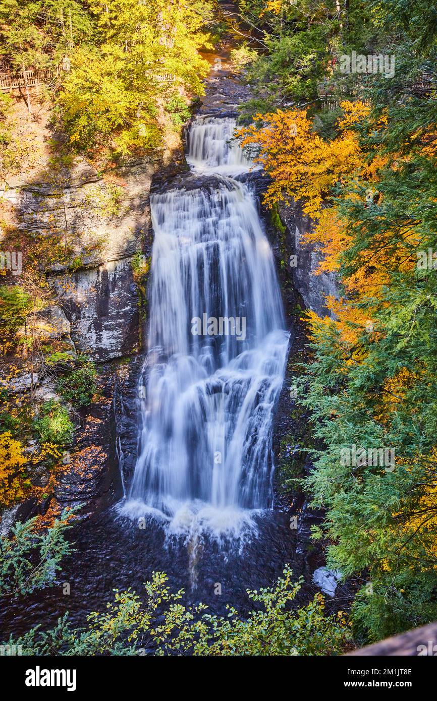 Vertical close of large waterfall from above surrounded by cliffs and ...