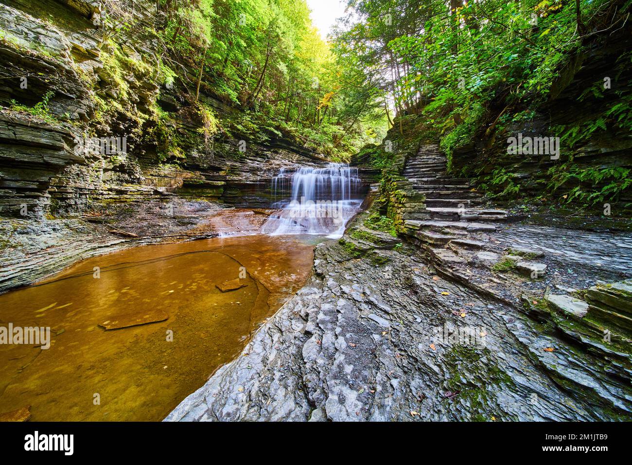 Rocky gorge from ground level with view of large waterfall and stone ...