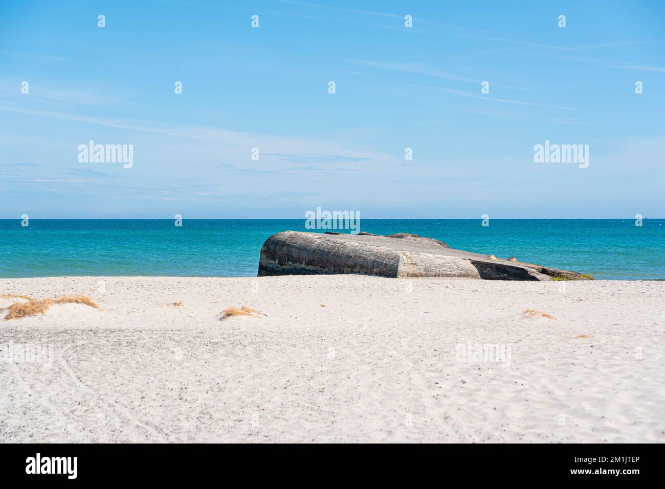 A sandy beach and war bunker by the sea and blue sky on a summer day ...