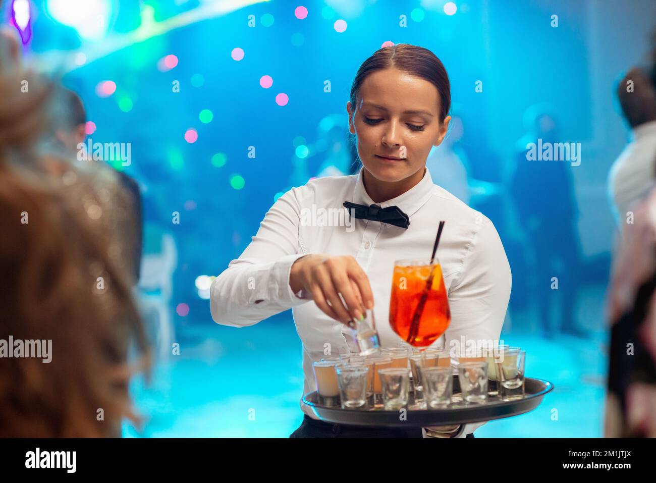 A young professional waitress serving drinks cocktails during a Party ...
