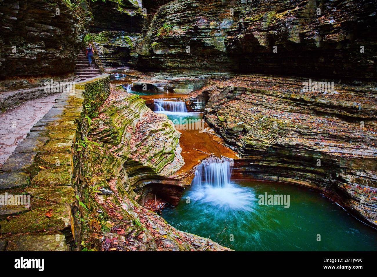 Fall foliage covering terraced rocks in gorge with stone path and ...