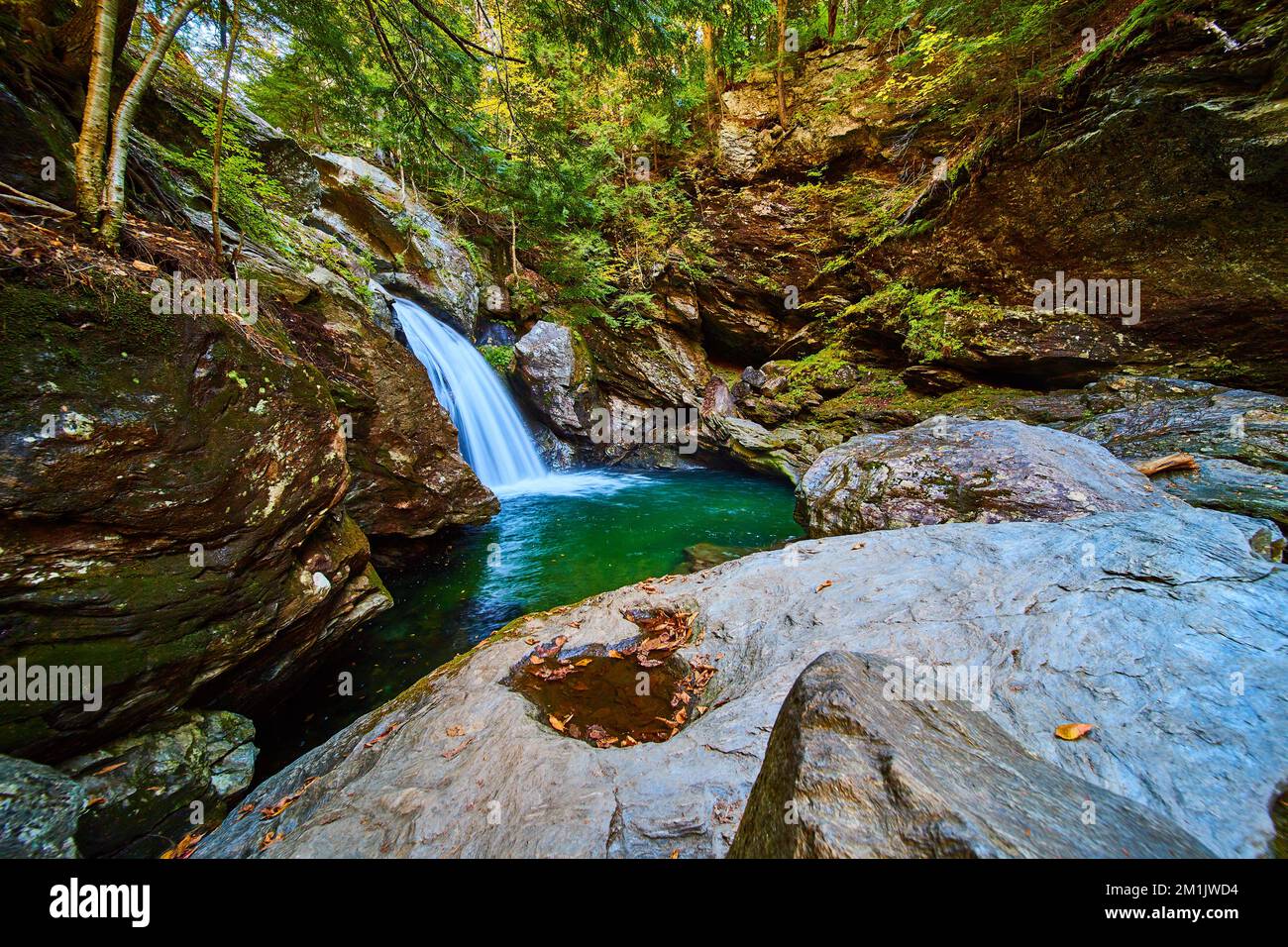 Beautiful blue waters from waterfall over cliffs surrounded in boulders ...