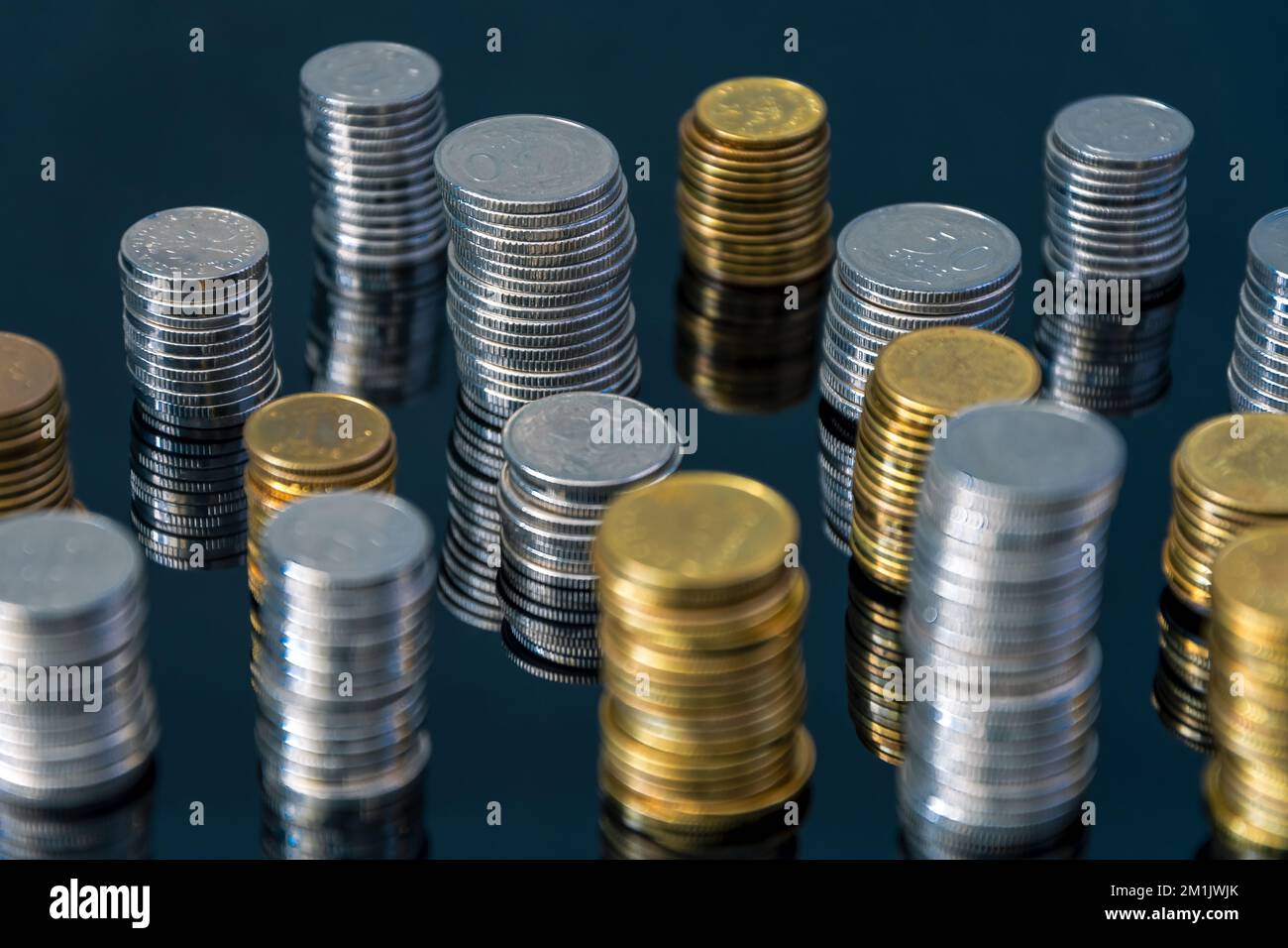 Piles of coins (polish zloty, grosze, PLN) on a black, reflective ...