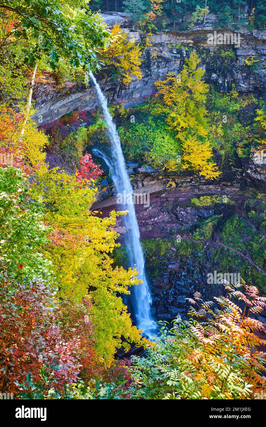 Stunning tall waterfall over cliffs is surrounded by colorful peak fall ...