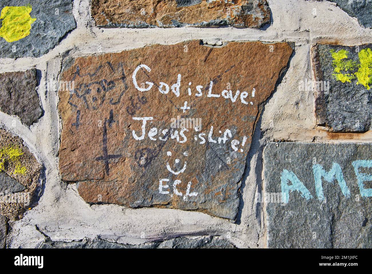 Detail down on stone wall graffiti God is Love Jesus is Life smiling ...