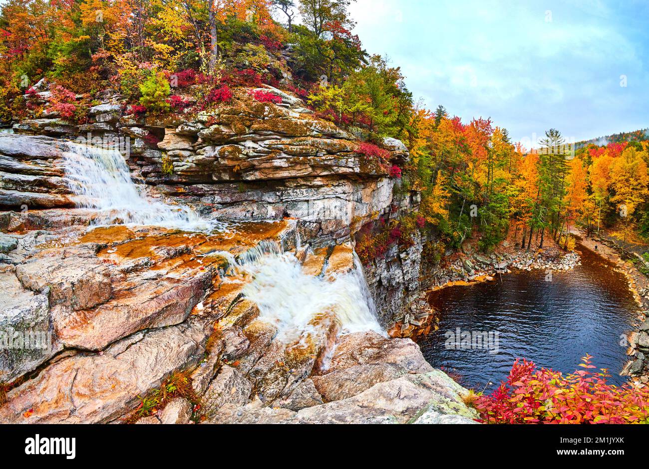 Cascading falls drop off cliff edge into body of water during colorful ...