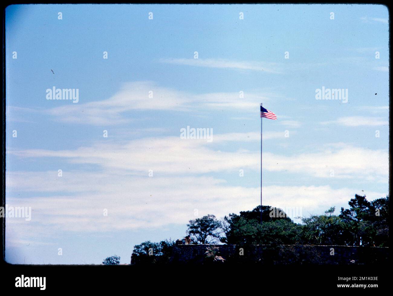 American flag seen above stone wall and trees, Grand Canyon, Arizona ...