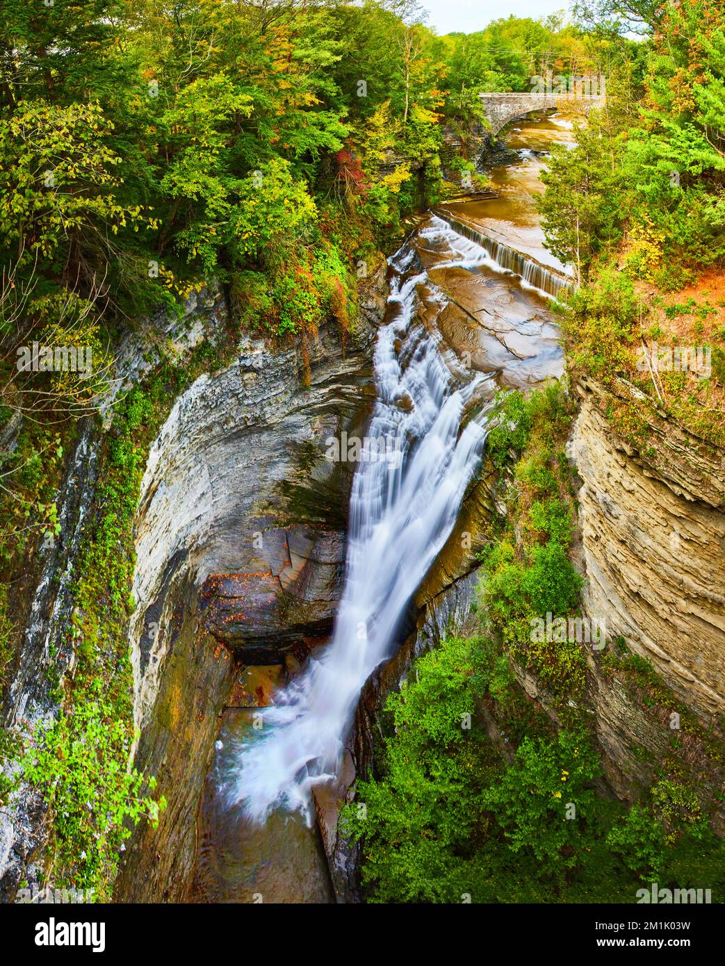 Stunning large waterfall into deep gorge with stone bridge in ...
