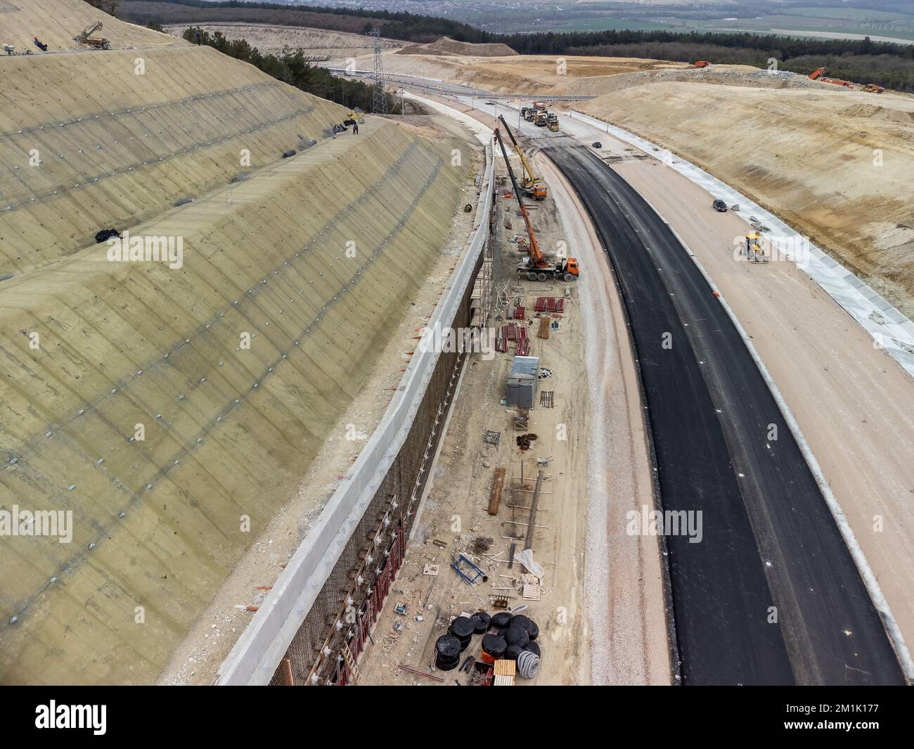 Mountain road constraction. Workers reinforce the slope over the new ...