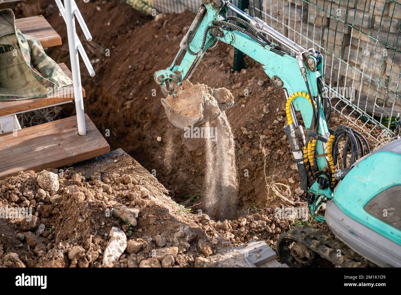 Mini excavator digs a trench to lay pipes. Close up of an excavator ...