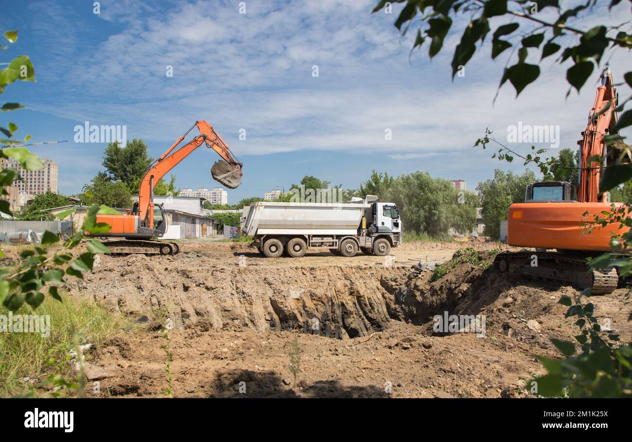 two orange tracked excavators and a gray dump truck in the process of excavation. Site ...