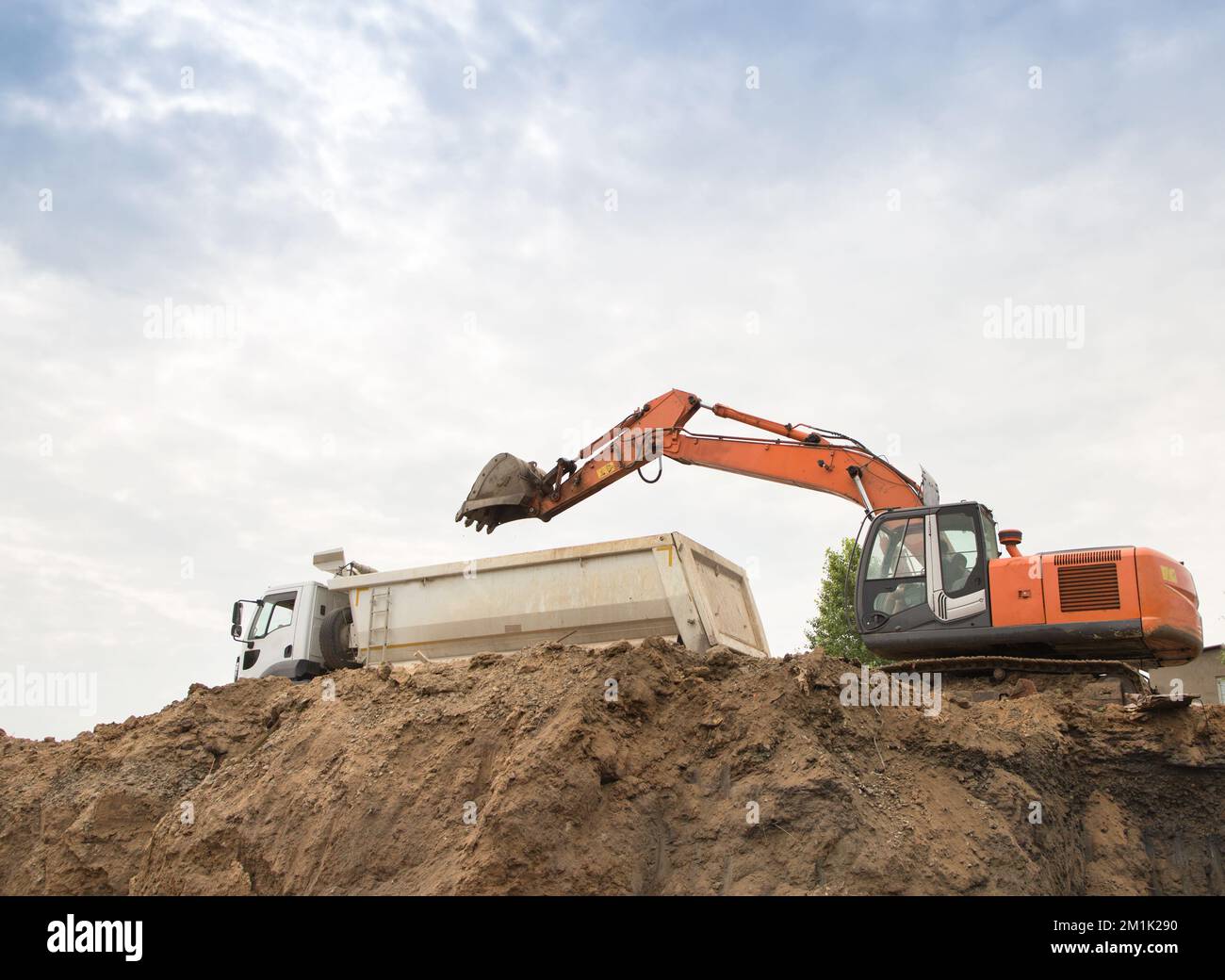 orange crawler excavator and gray dump truck at the stage of earthworks ...