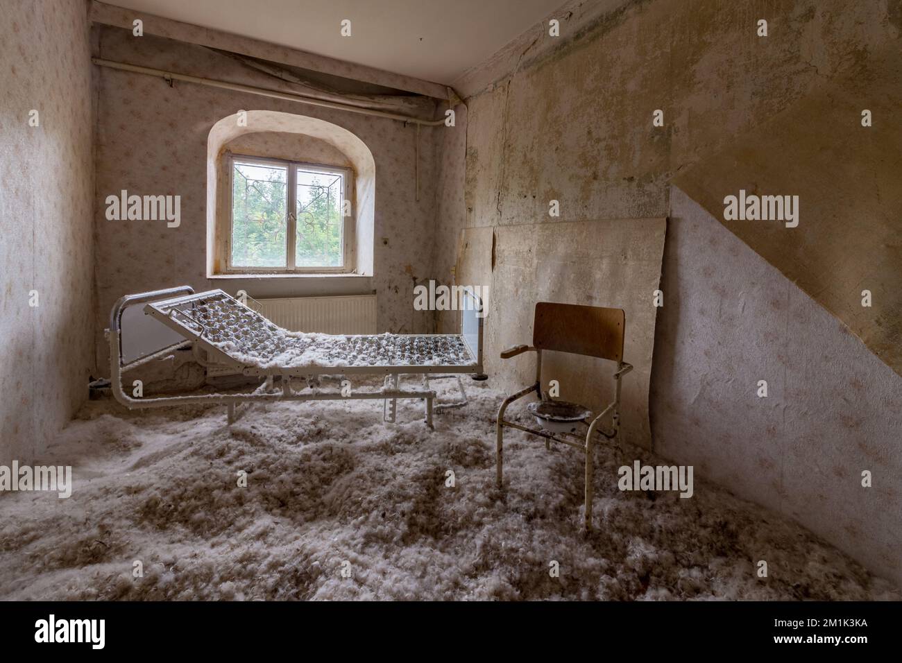The frame of an old bed and chamber pot in an old room with wool all ...