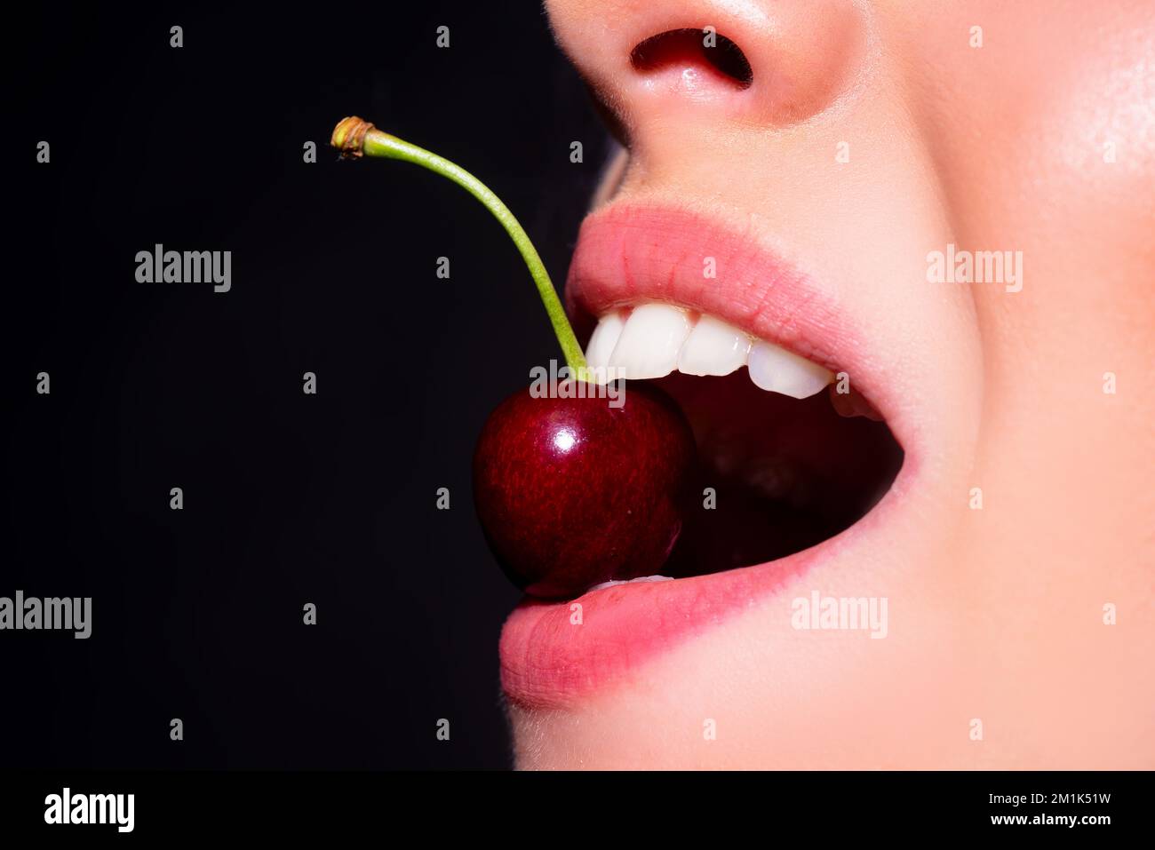 Cherry in teeth, macro, close up. Cherry in woman mouth. Cherries on woman lips. Girl biting ...
