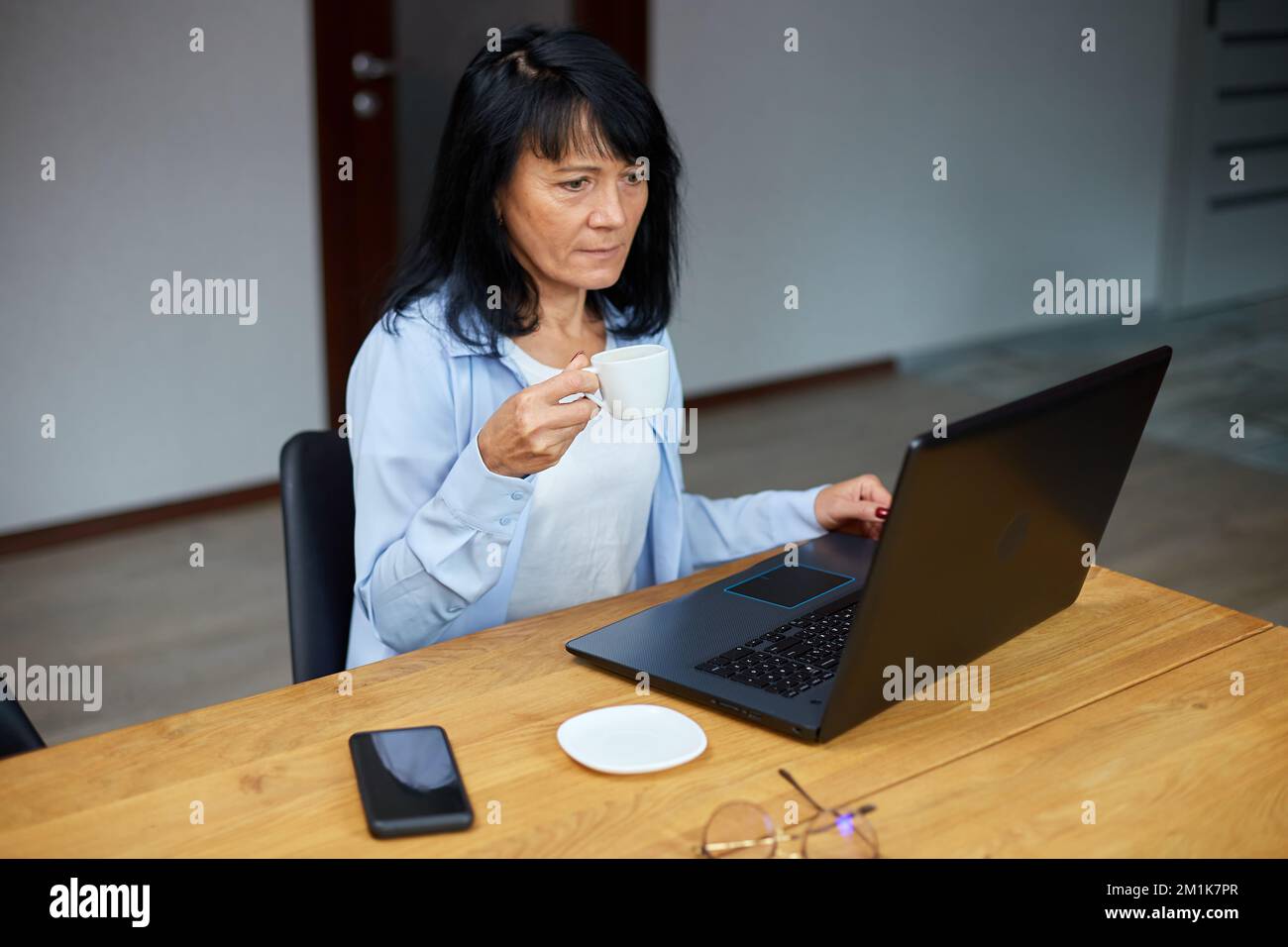 Elderly lady businesswoman relaxing at workplace, drinking coffee while ...