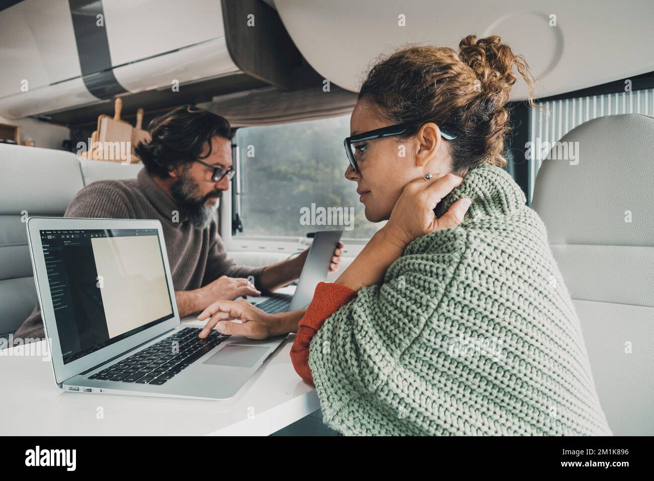 Couple of traveler worker using laptop together inside a camper van ...