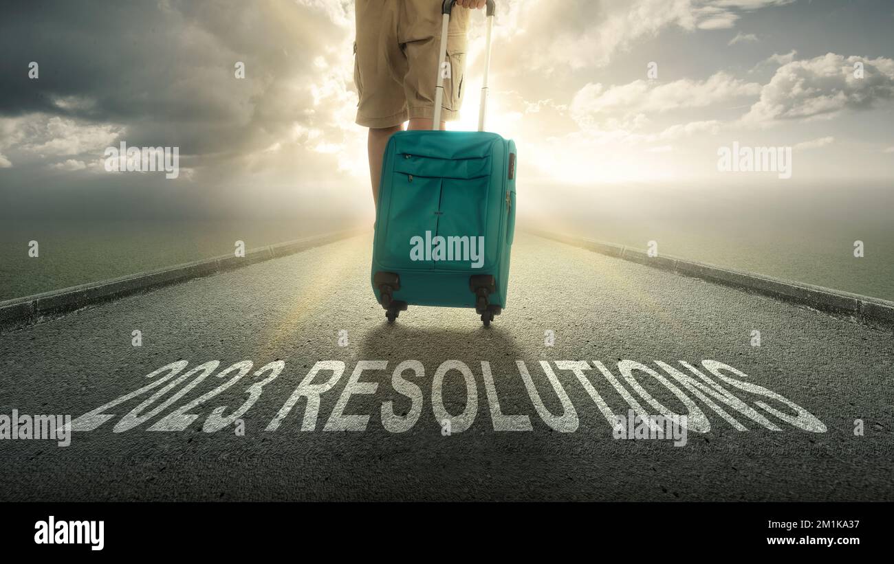 Rear view of man with suitcase walking on 2023 resolution street ...