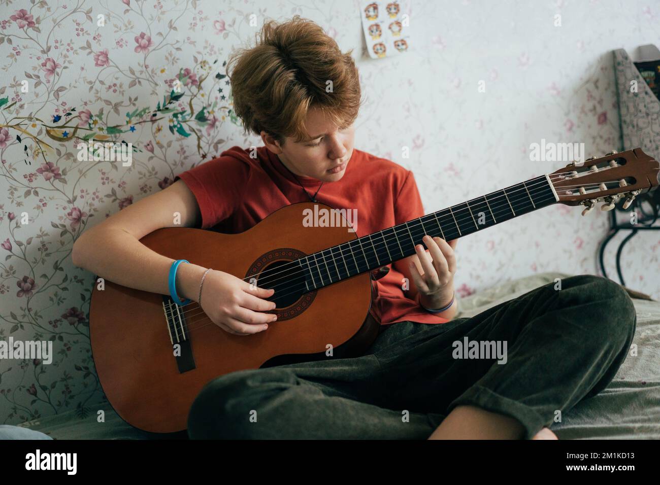 Romantic adolescent redhead girl learning to play the guitar while ...