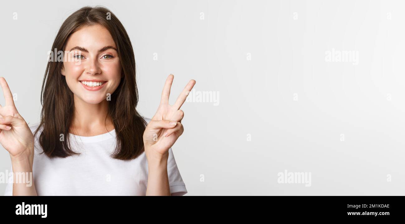 Portrait of beautiful and happy brunette girl smiling and showing peace ...