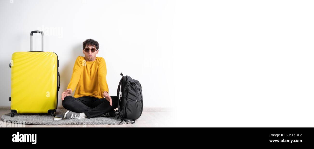 Young traveler man with suitcase looking in camera with raised eyebrows ...