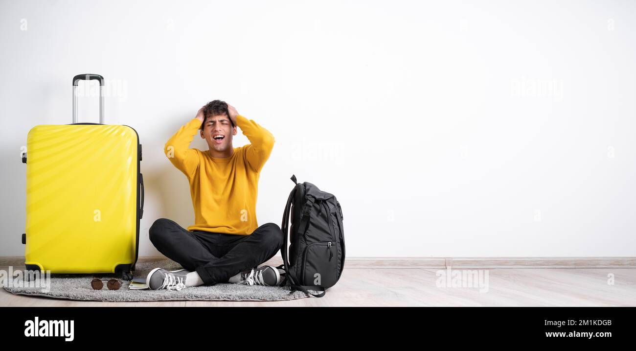 Sick traveler with headache sitting with suitcase over isolated white ...