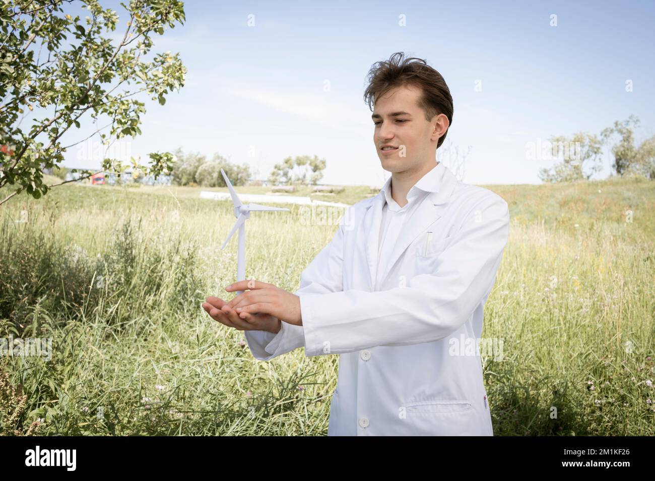 young scientist, student with model of wind turbine standing outside in ...