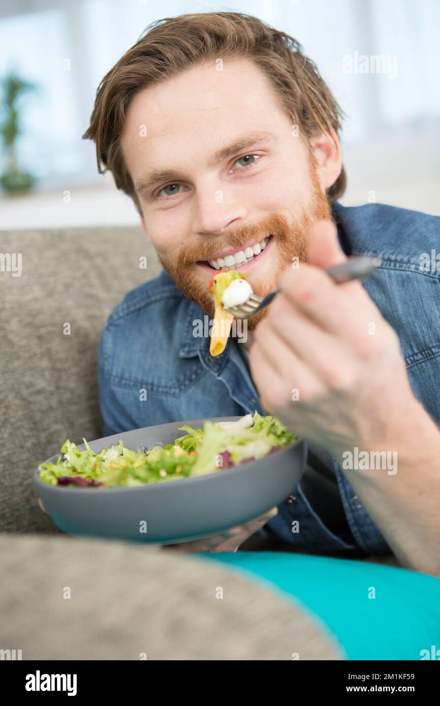 man laid on the sofa eating a salad Stock Photo - Alamy