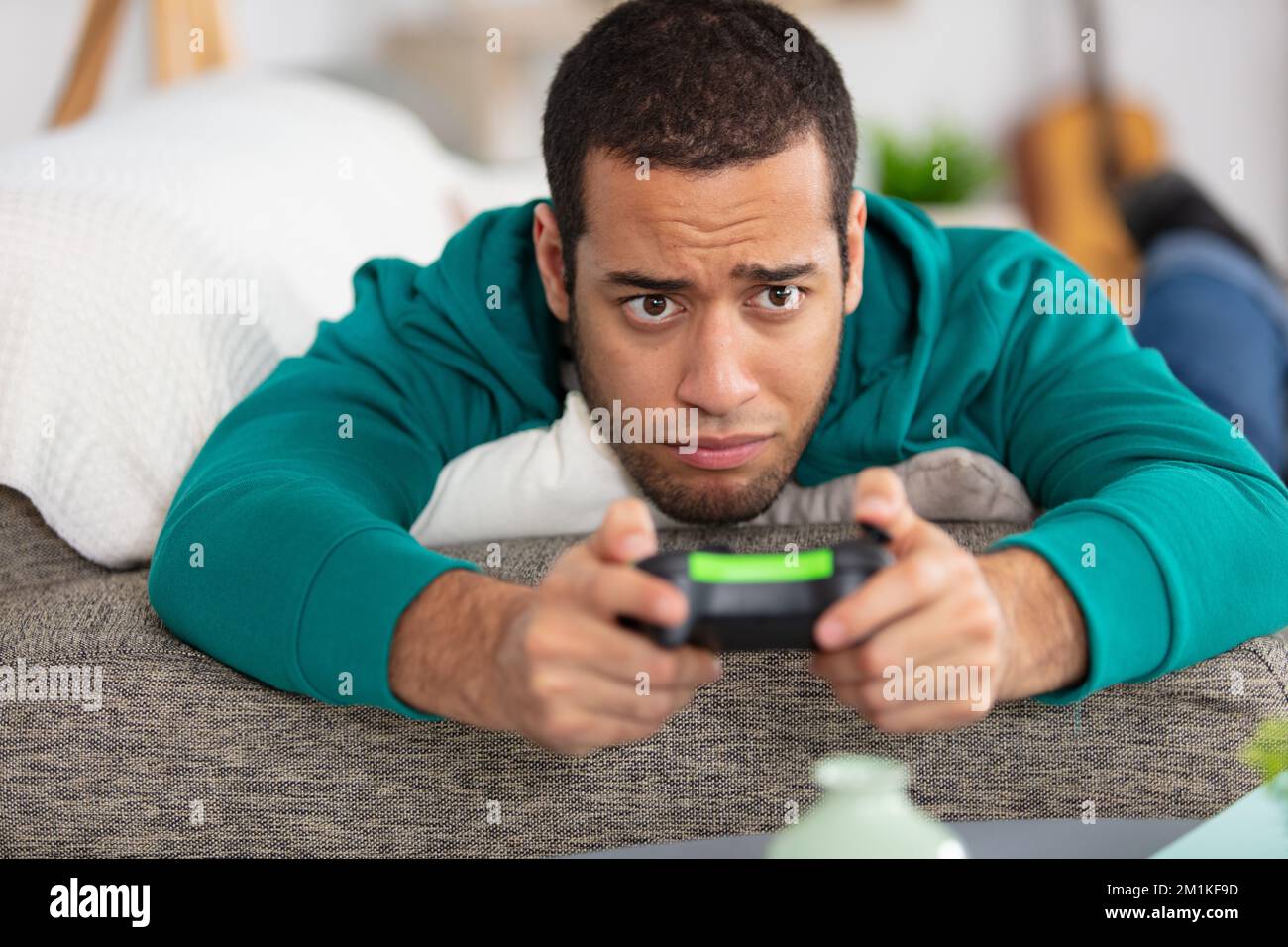 young guy playing computer game leaning over sofa Stock Photo - Alamy