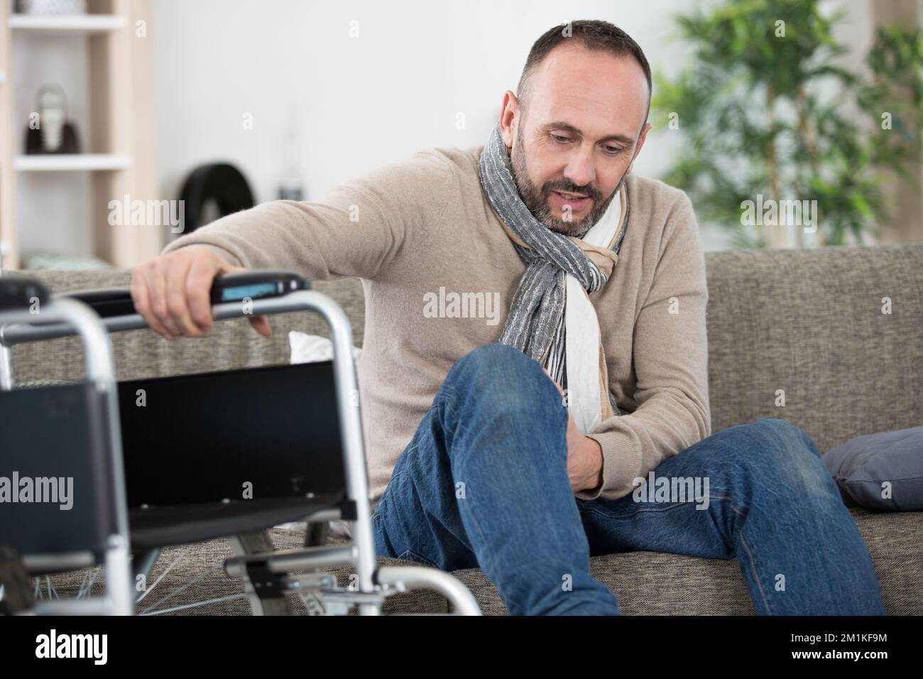 disabled man moving his leg on to the sofa Stock Photo - Alamy