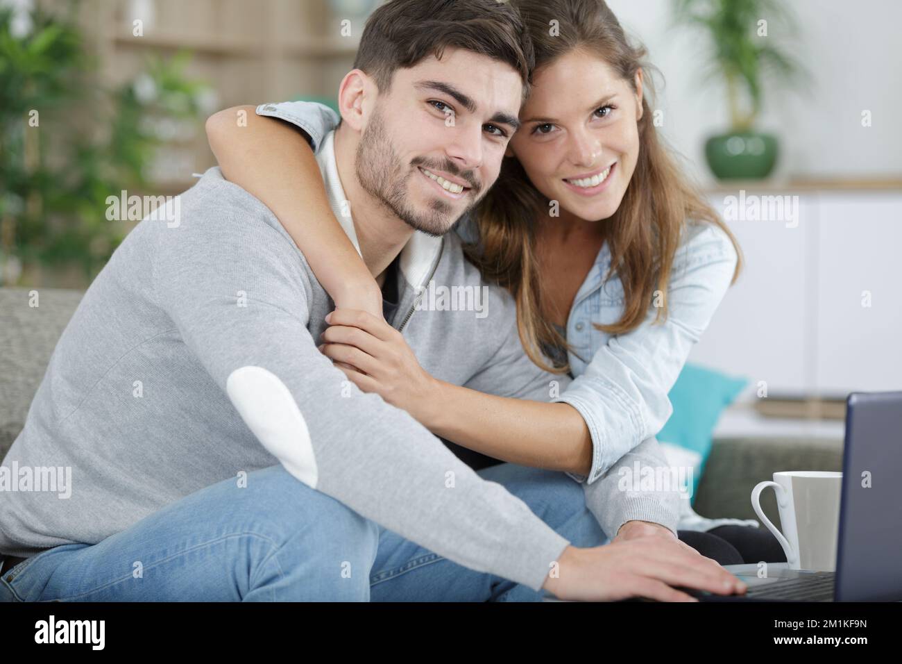 couple hugging and sitting with laptop Stock Photo - Alamy