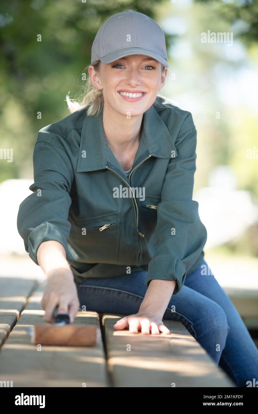 women worker varnishing park benches Stock Photo - Alamy