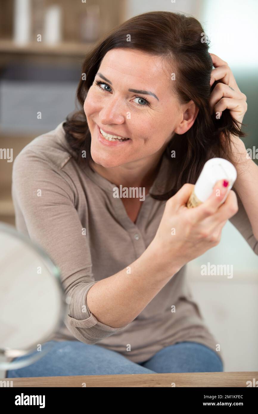 beautiful woman applying hair spray on her hair Stock Photo - Alamy