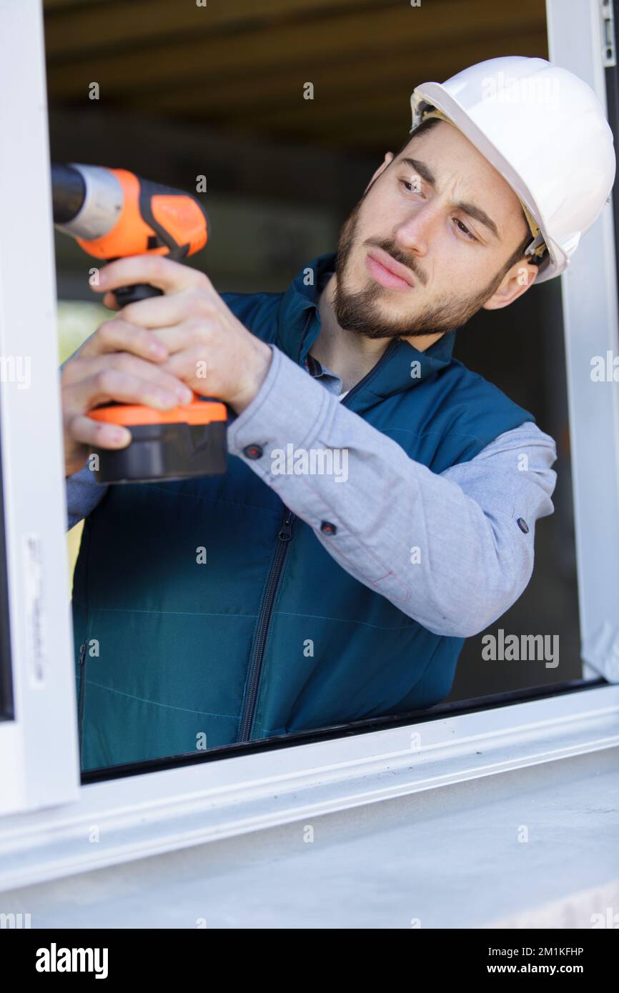 man is drilling a window frame Stock Photo - Alamy