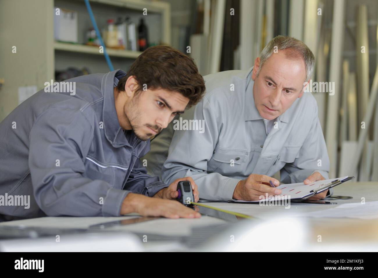 workmen using tapemeasure and holding clipboard Stock Photo - Alamy