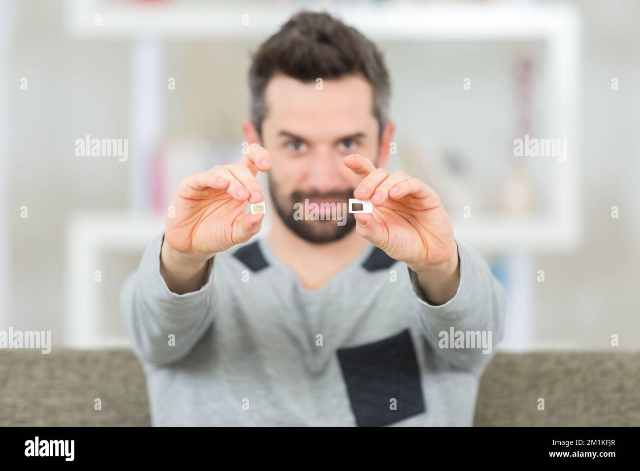 portrait of man holding a sim card in each hand Stock Photo - Alamy