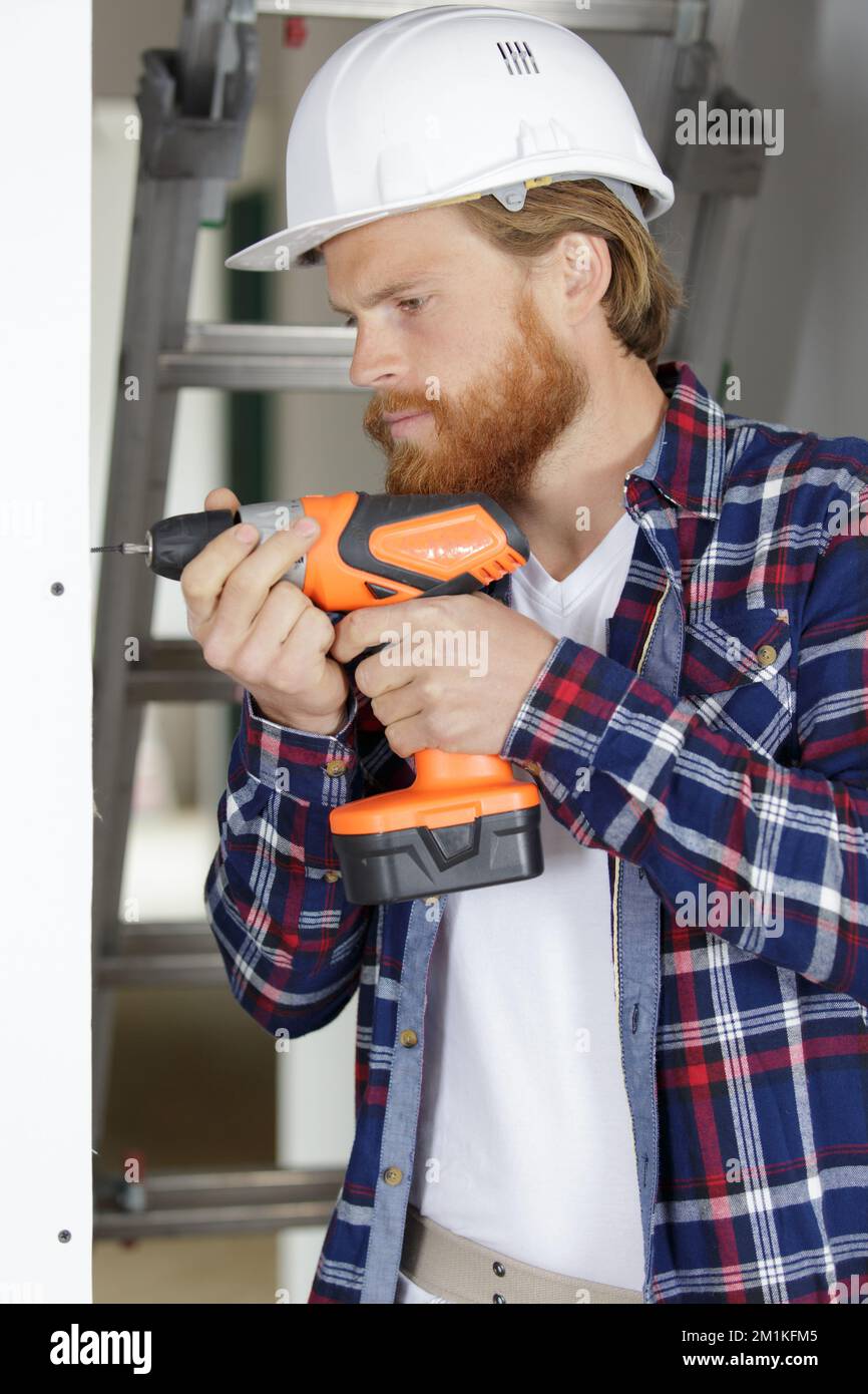 man twists a screw into the wall Stock Photo - Alamy