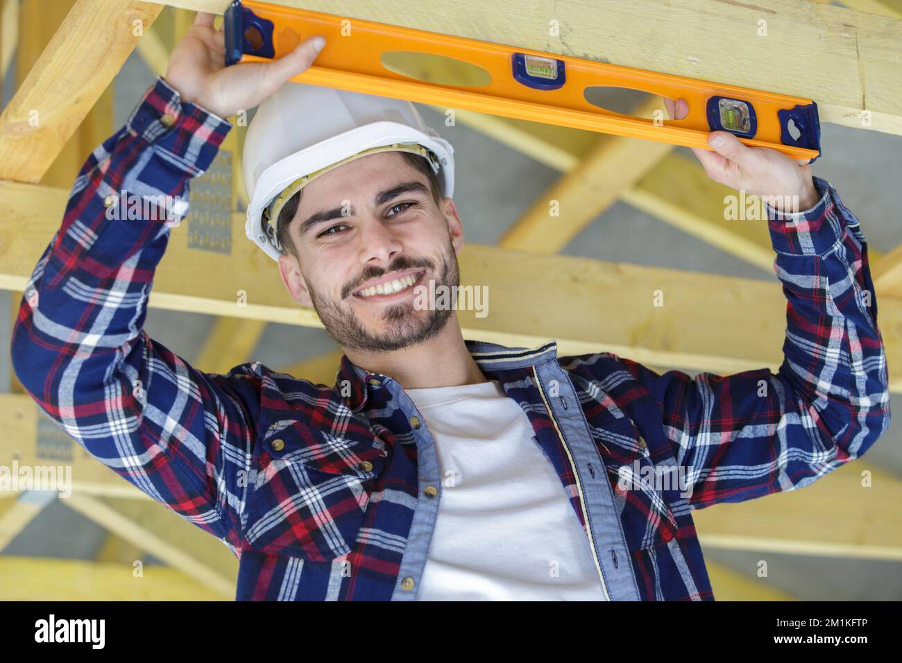 male construction worker using spirit level on wooden beam Stock Photo ...
