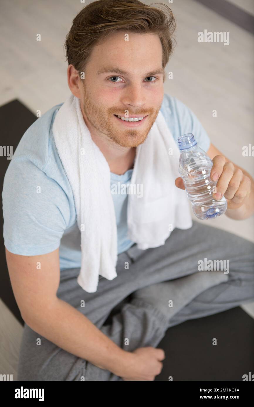 man on exercise mat drinking water from plastic bottle Stock Photo - Alamy