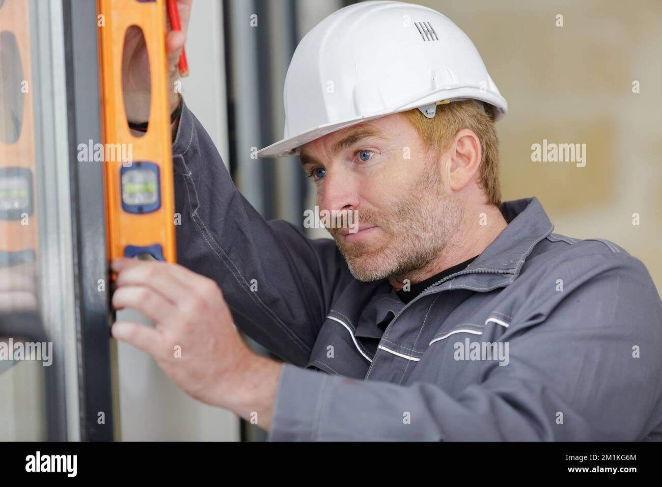 builder positioning spirit level vertically and observing Stock Photo ...