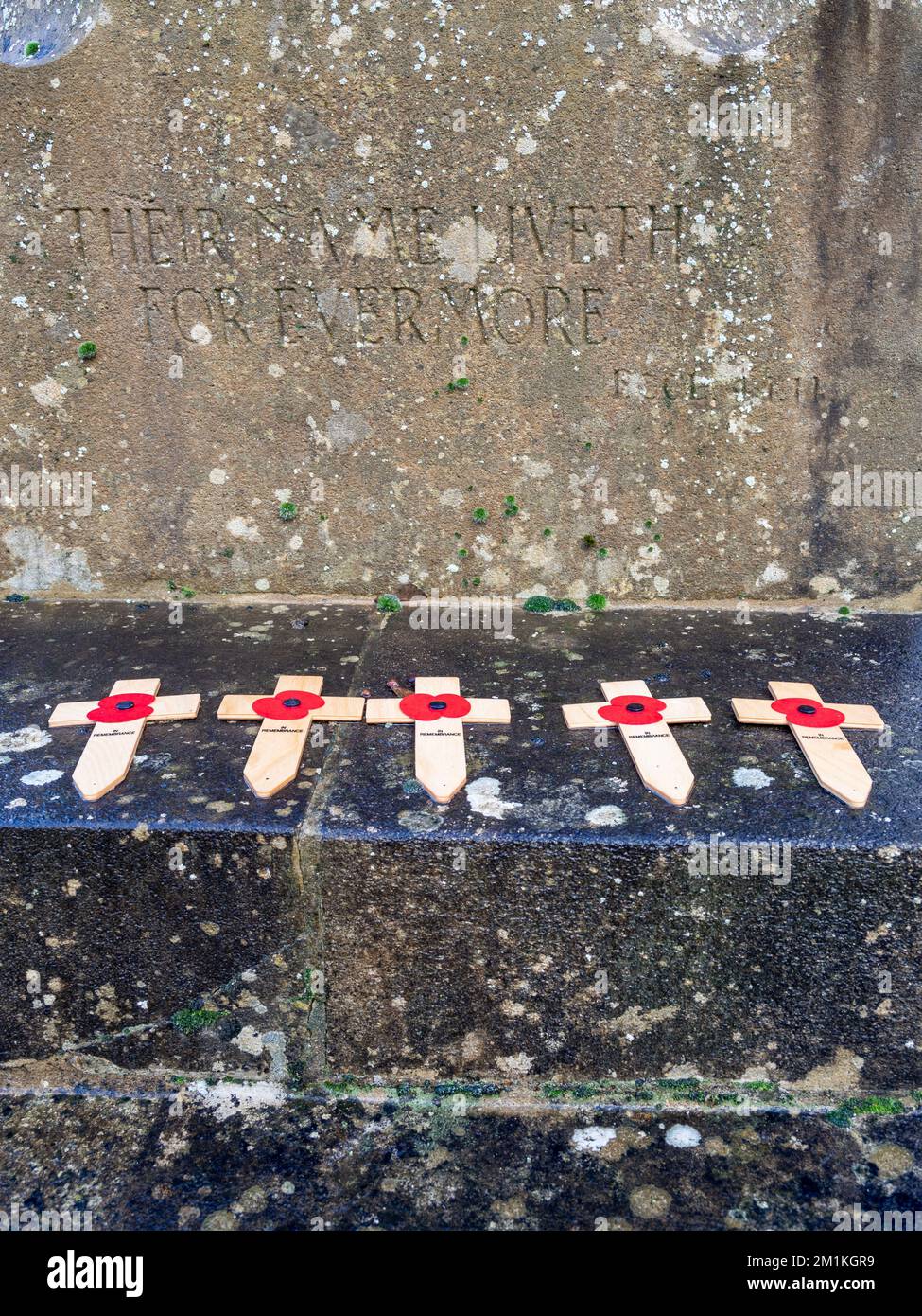 Wooden crosses with artificial poppies on the base of a war memorial ...