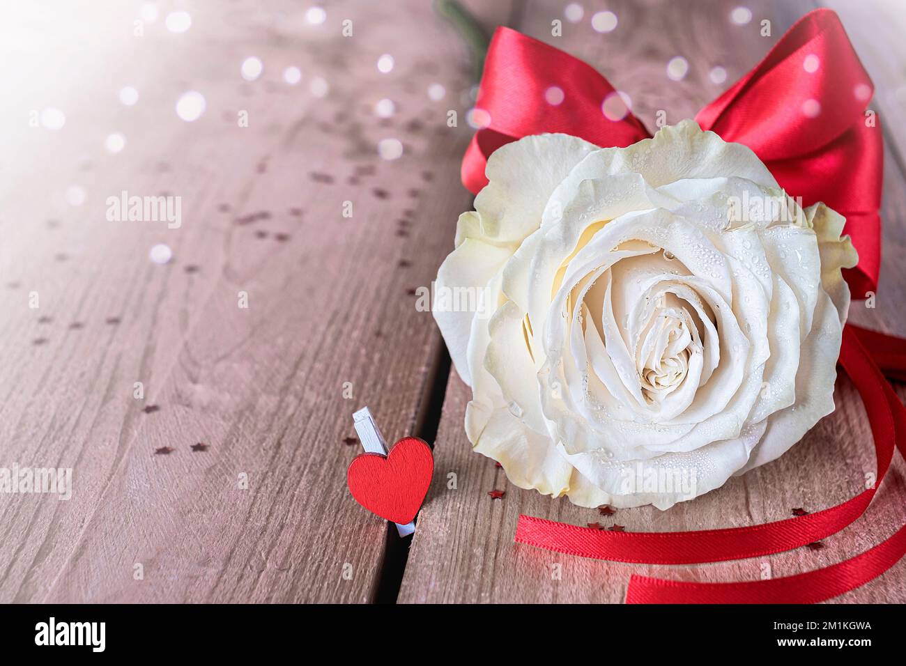 White rose witha red bow and small heart on wooden background Stock ...