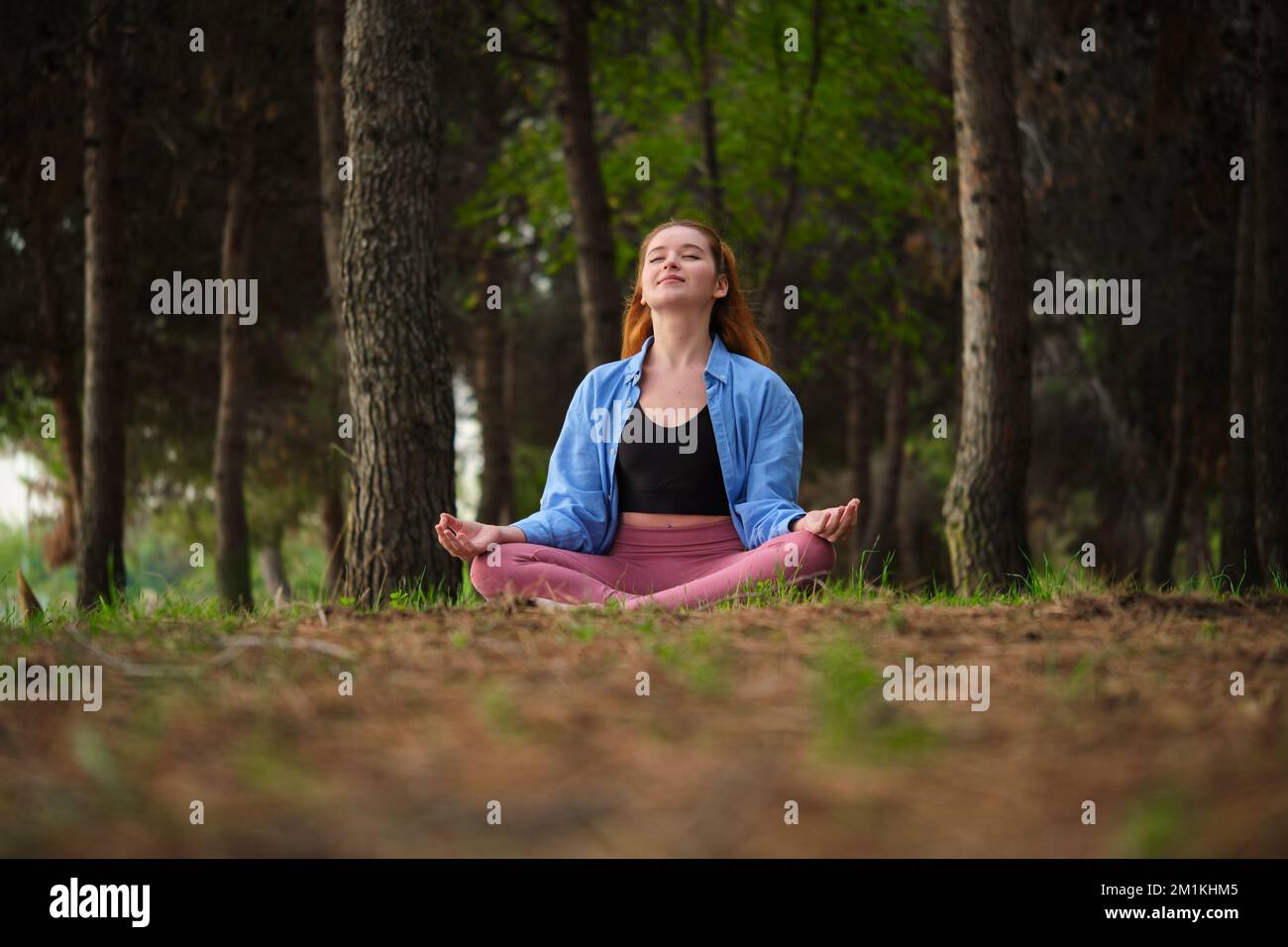 Redhead young woman meditating in a forest Stock Photo - Alamy