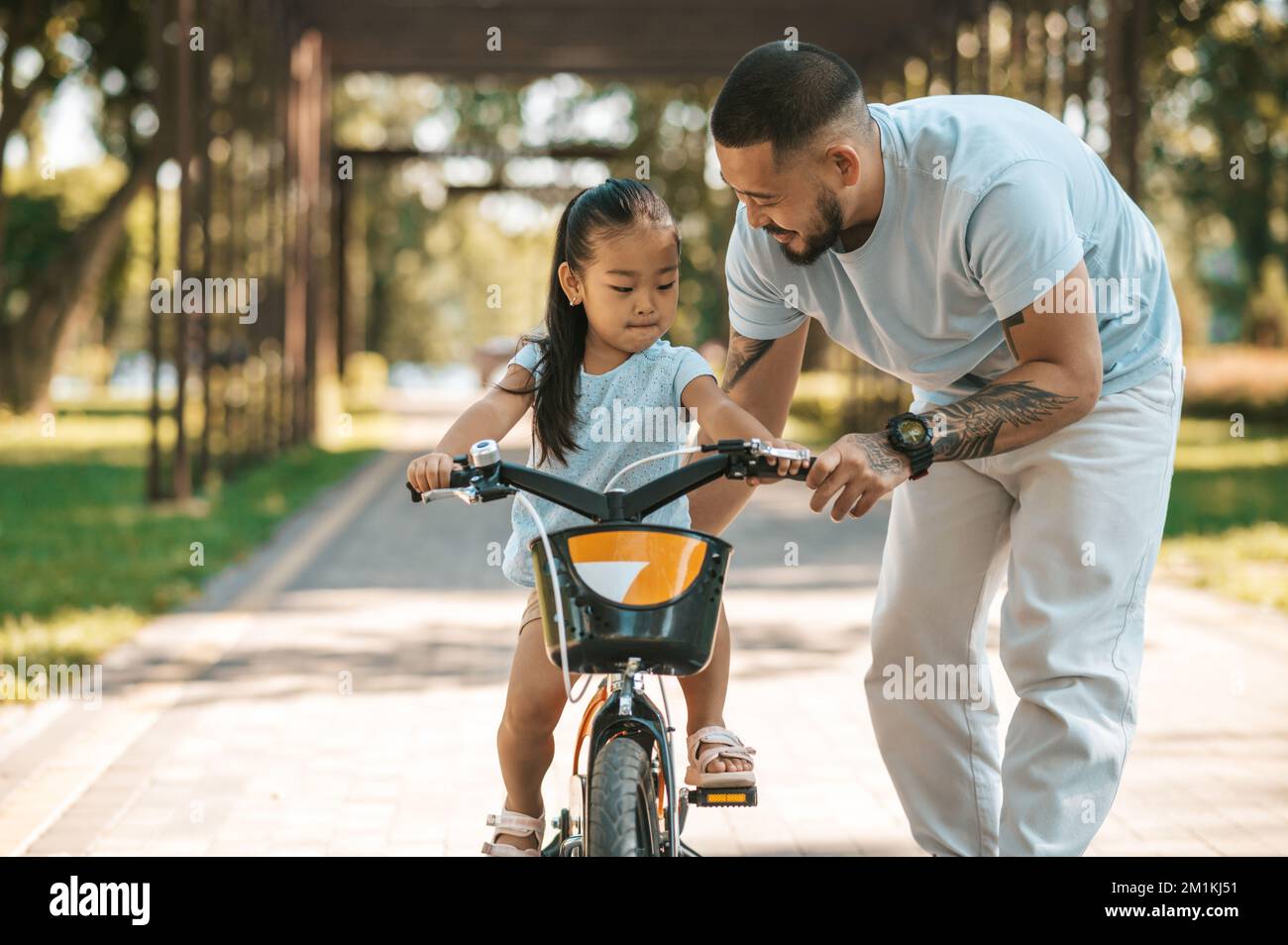 Young dad teaching his kid to ride a bike Stock Photo - Alamy
