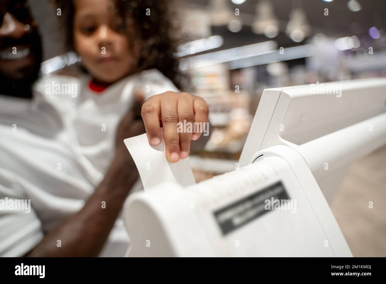 Young man holding a little girl ad she is taling a bill from cashier ...