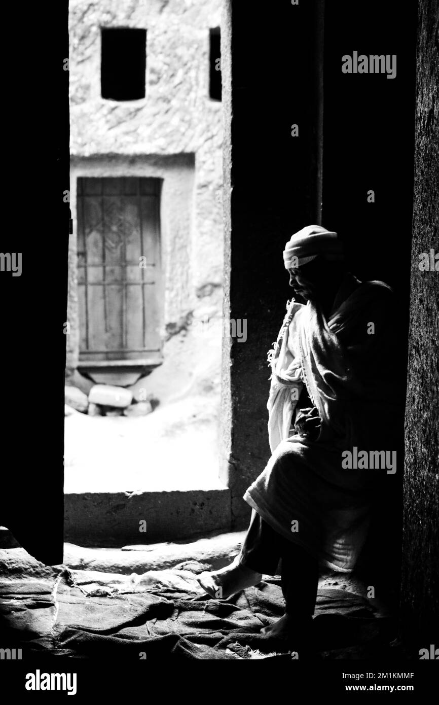 A grayscale vertical shot of a prayer inside an old rock church in ...