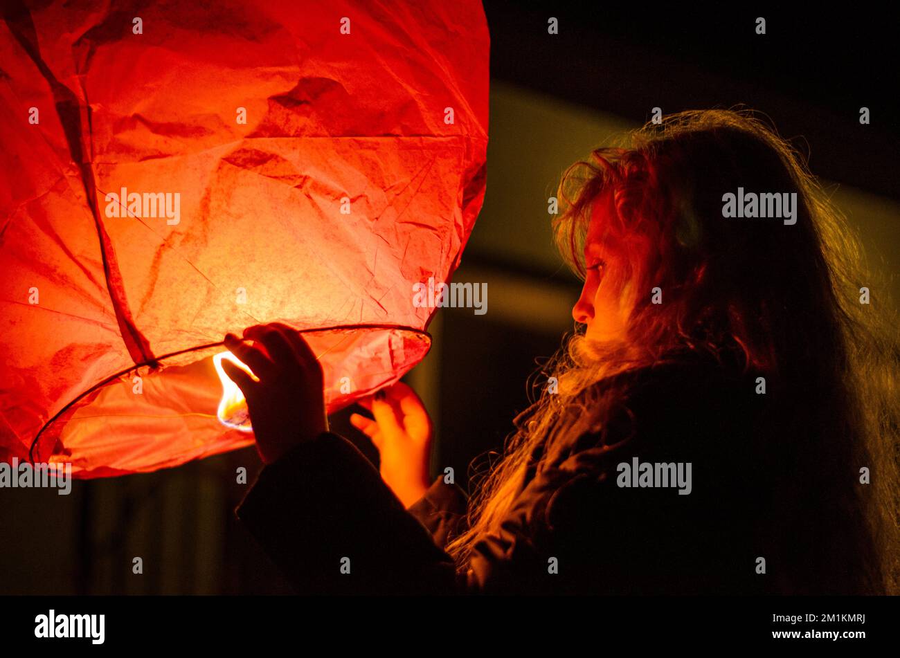 lovely girl with orange fortune paper balloon in hands prepared to fly ...