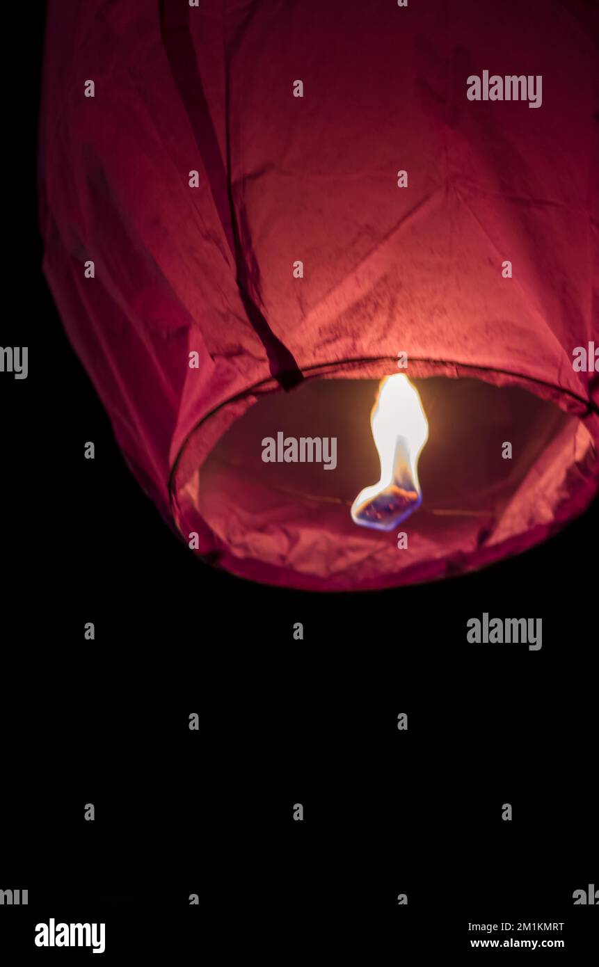 orange fortune paper balloon flying away into dark sky, isolated, black ...